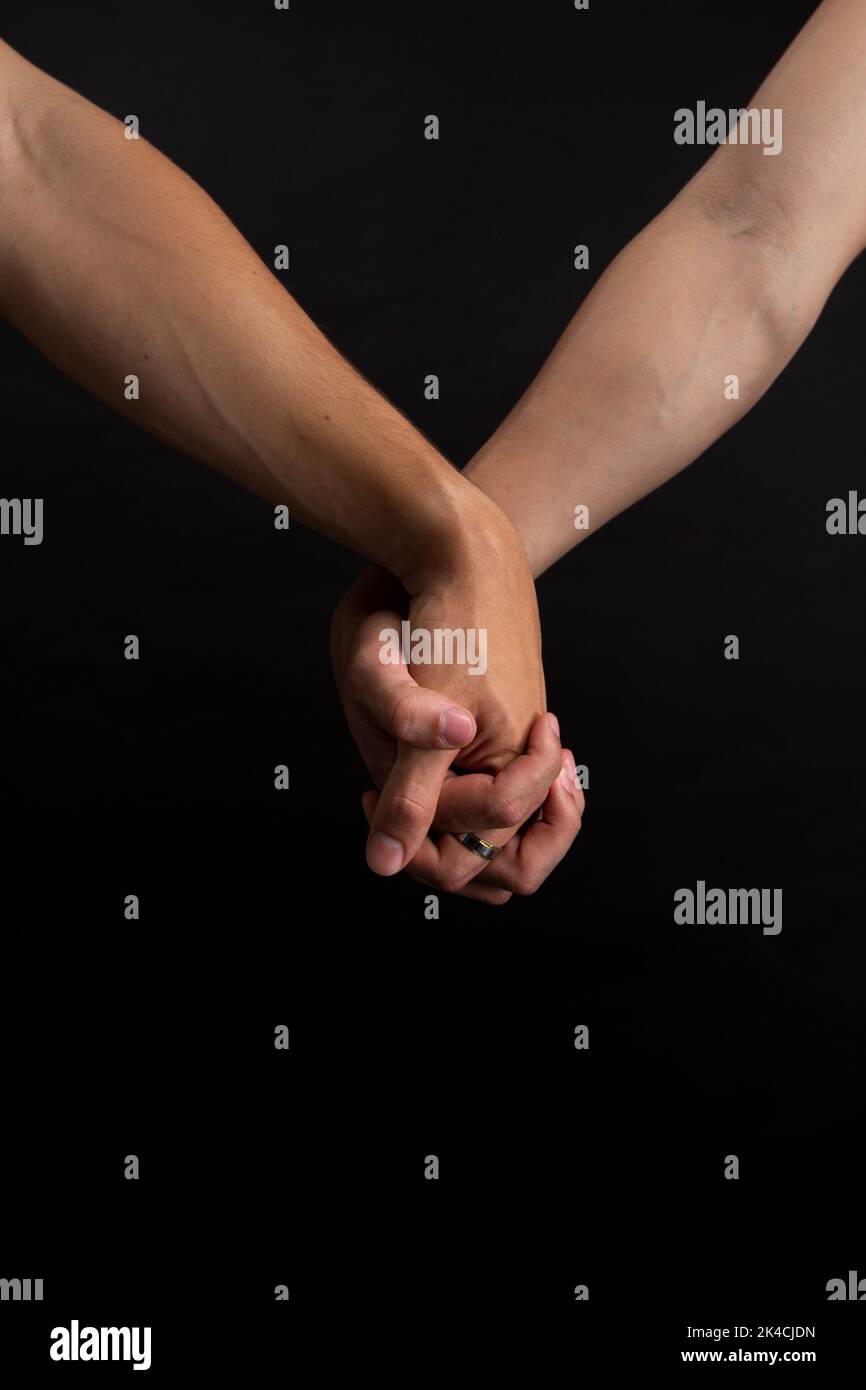 The two people holding each other hands on the black background ...