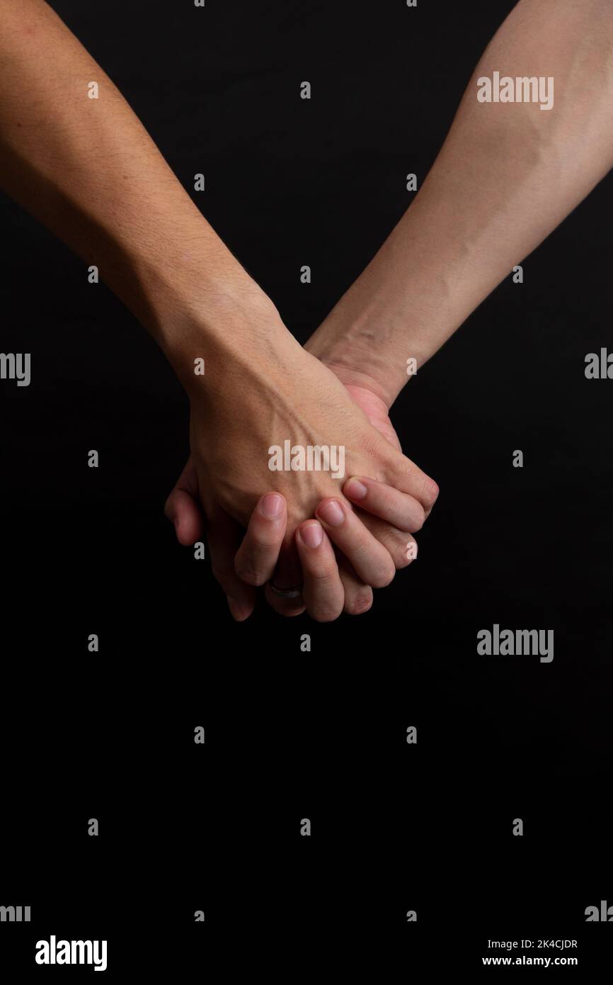 The two people holding each other hands on the black background ...
