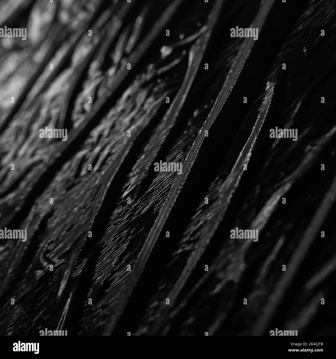Reflecting light and shadow on creases and folds in black plastic ...