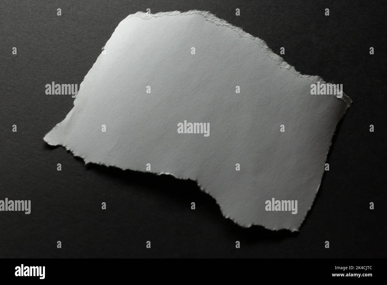 Roughly torn rectangle of white paper on black background. monochrome ...