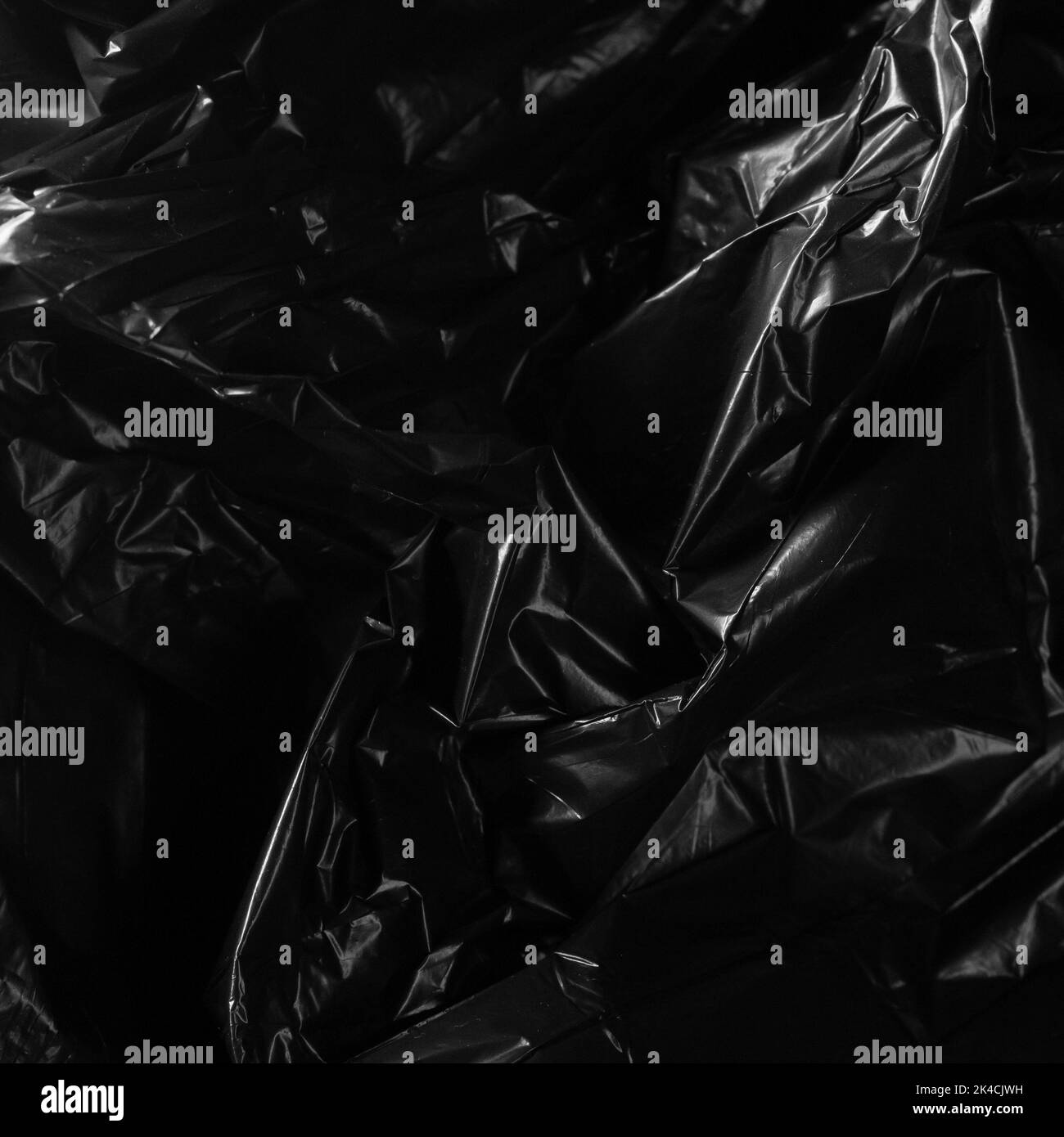 Reflecting light and shadow on creases and folds in scrunched black ...