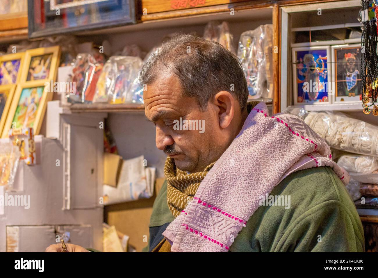A portrait of an old Indian shopkeeper with a towel on the shoulder ...
