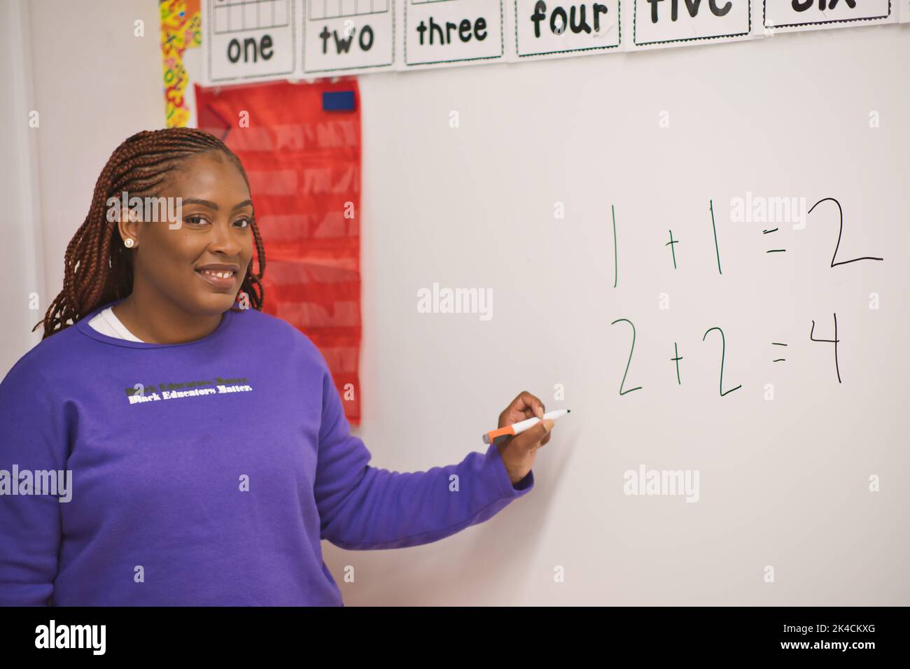 A confident African American female math teacher writing number on the ...