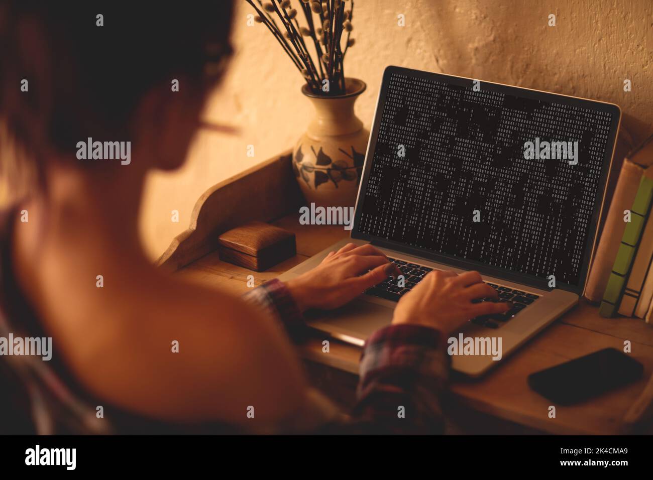 Back View Of Caucasian Female Programmer Sitting At Desk Using Laptop With Coding On Screen