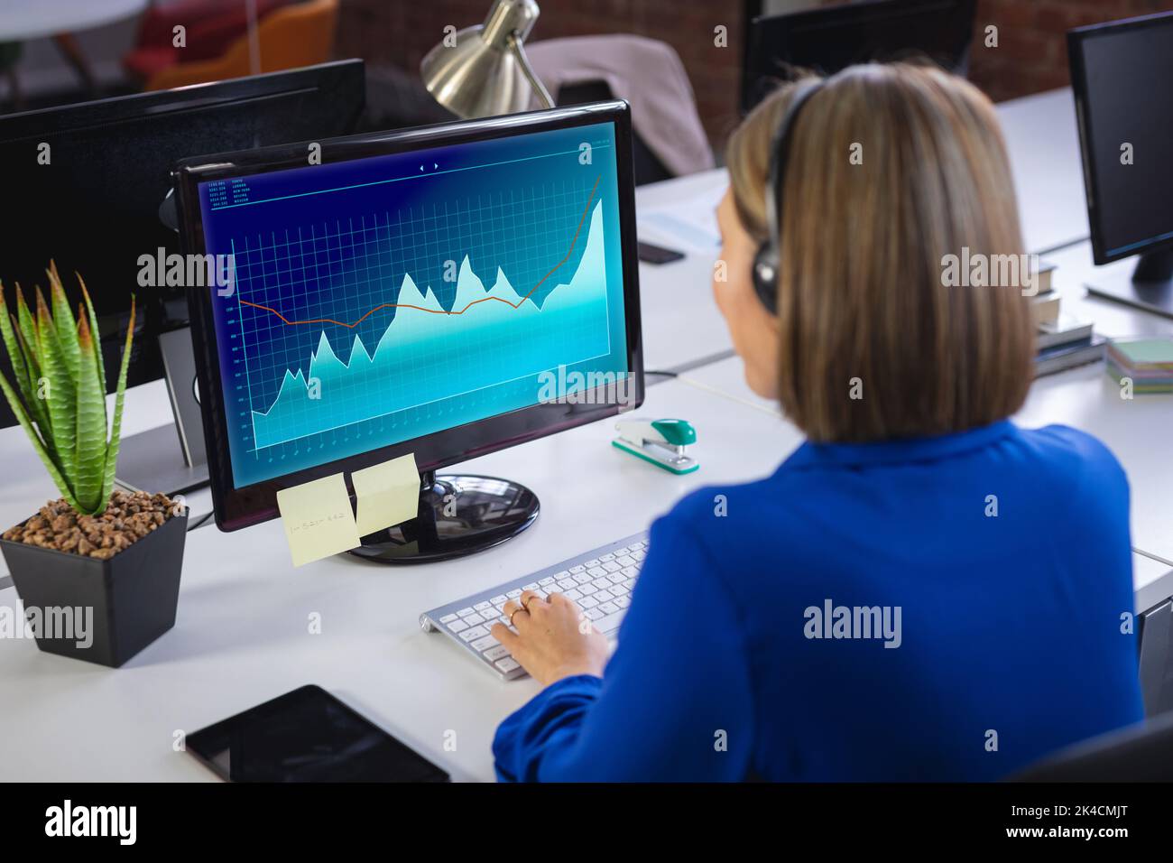 Caucasian businesswoman sitting at desk, using computer with ...