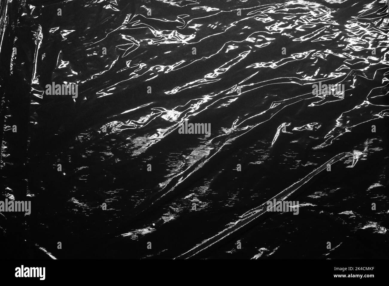 Reflecting light and shadow on creases and folds in black plastic ...