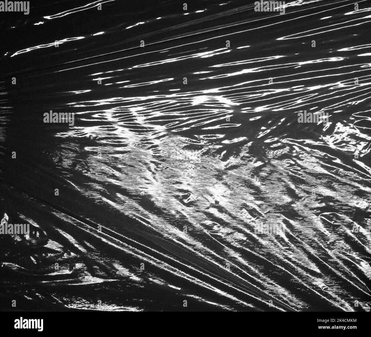 Reflecting light and shadow on creases and folds in black plastic ...