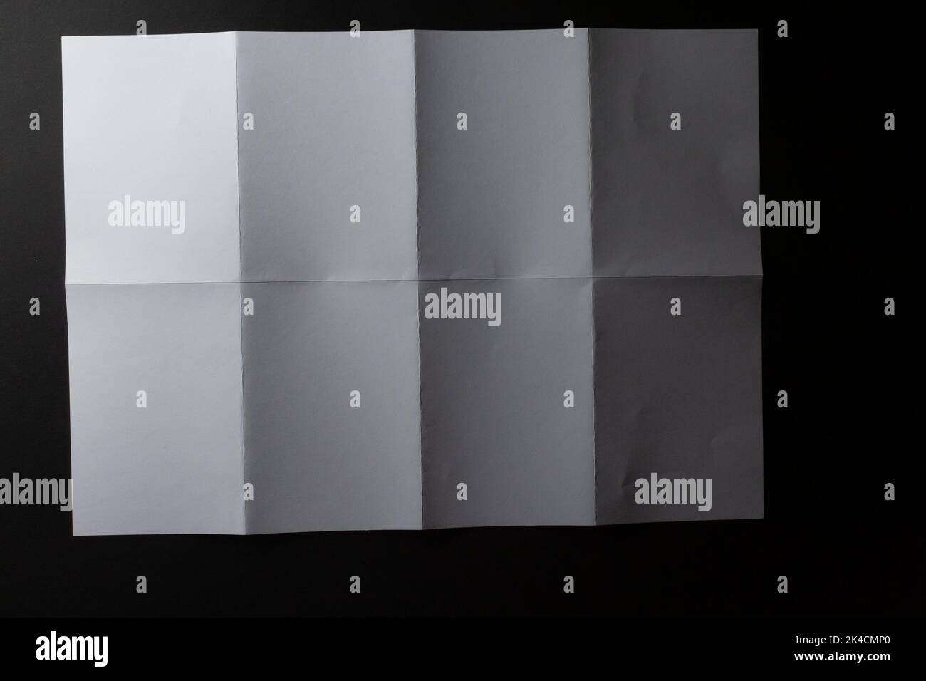 Light and shadow on creases in sheet of white paper folded into eight ...