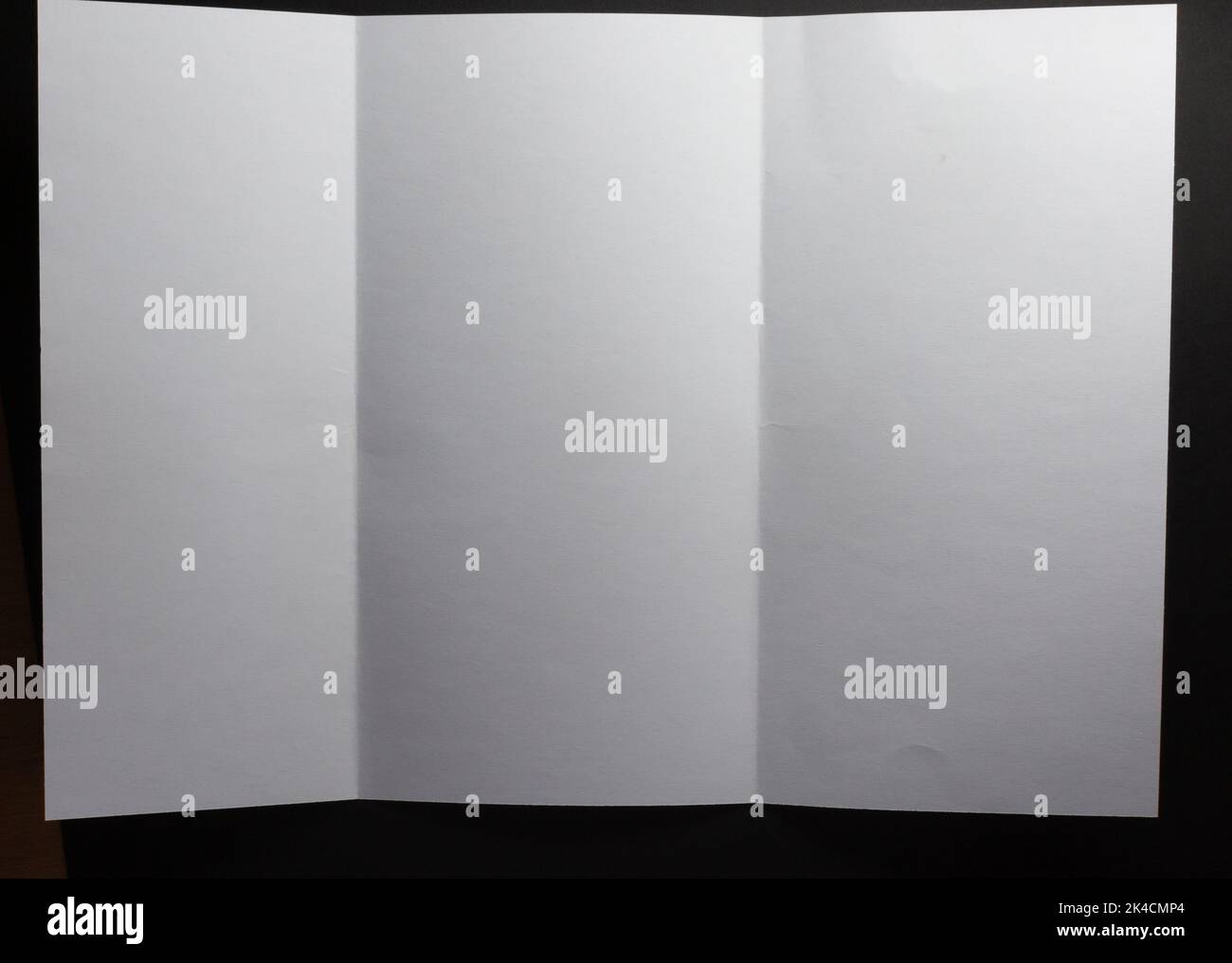 Light and shadow on creases in sheet of white paper folded into three ...