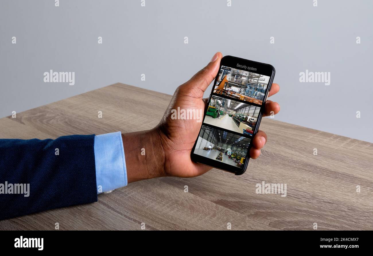 Hand of caucasian man holding smartphone with view of warehouse from ...