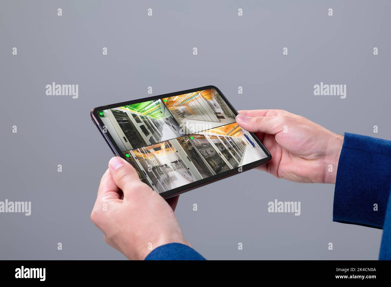 Hands of caucasian man holding tablet with view from security cameras ...