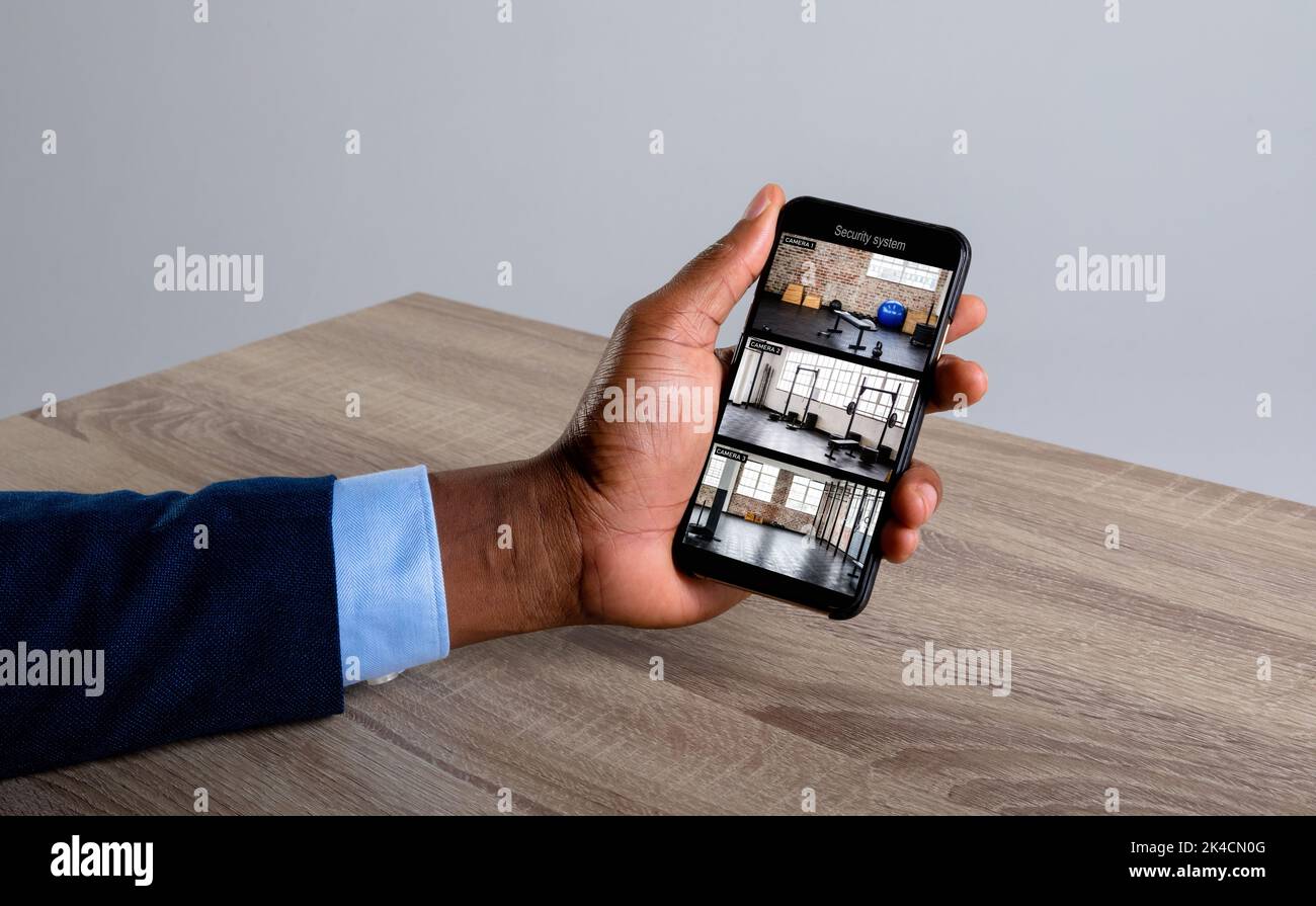 Hand of african american man holding smartphone with view of gym from ...