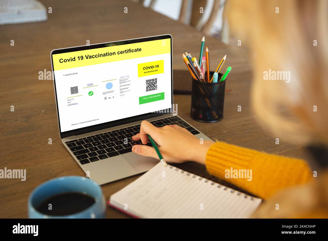 Caucasian woman using laptop with covid vaccination certificate and qr ...