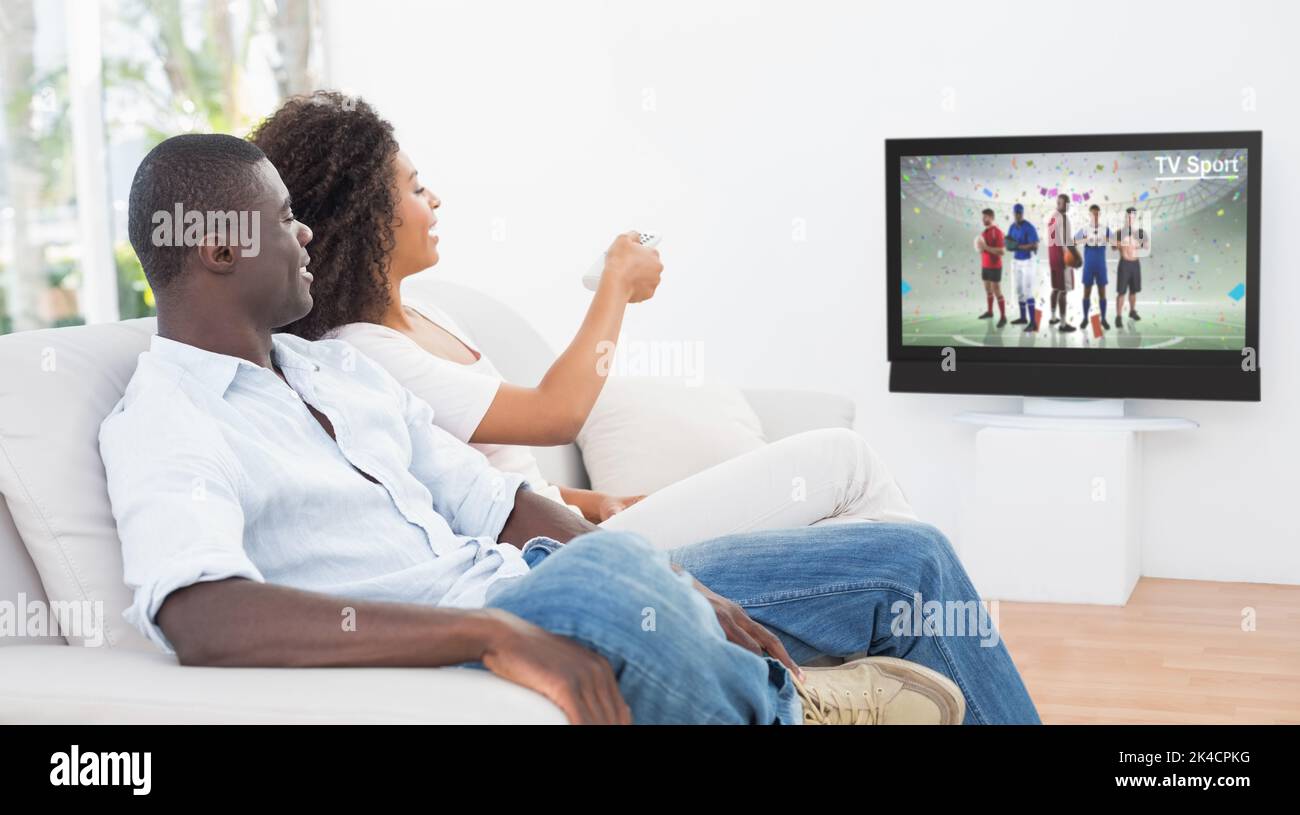 Couple sitting on couch together watching tv at home in the living room ...