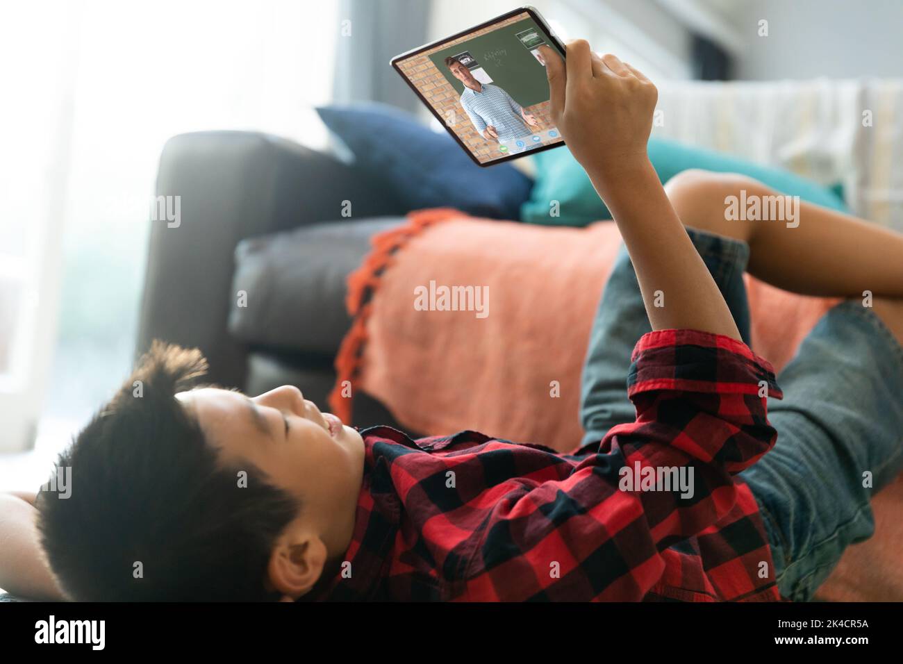 Smiling asian boy using tablet for video call, with caucasian male ...