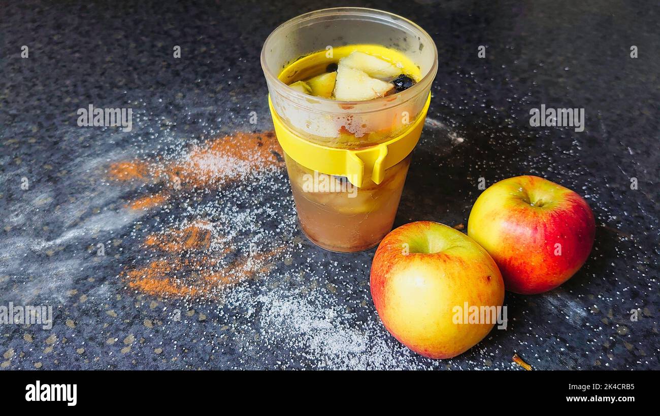 A closeup shot of a glass of apple tea and apples on a dirty kitchen ...