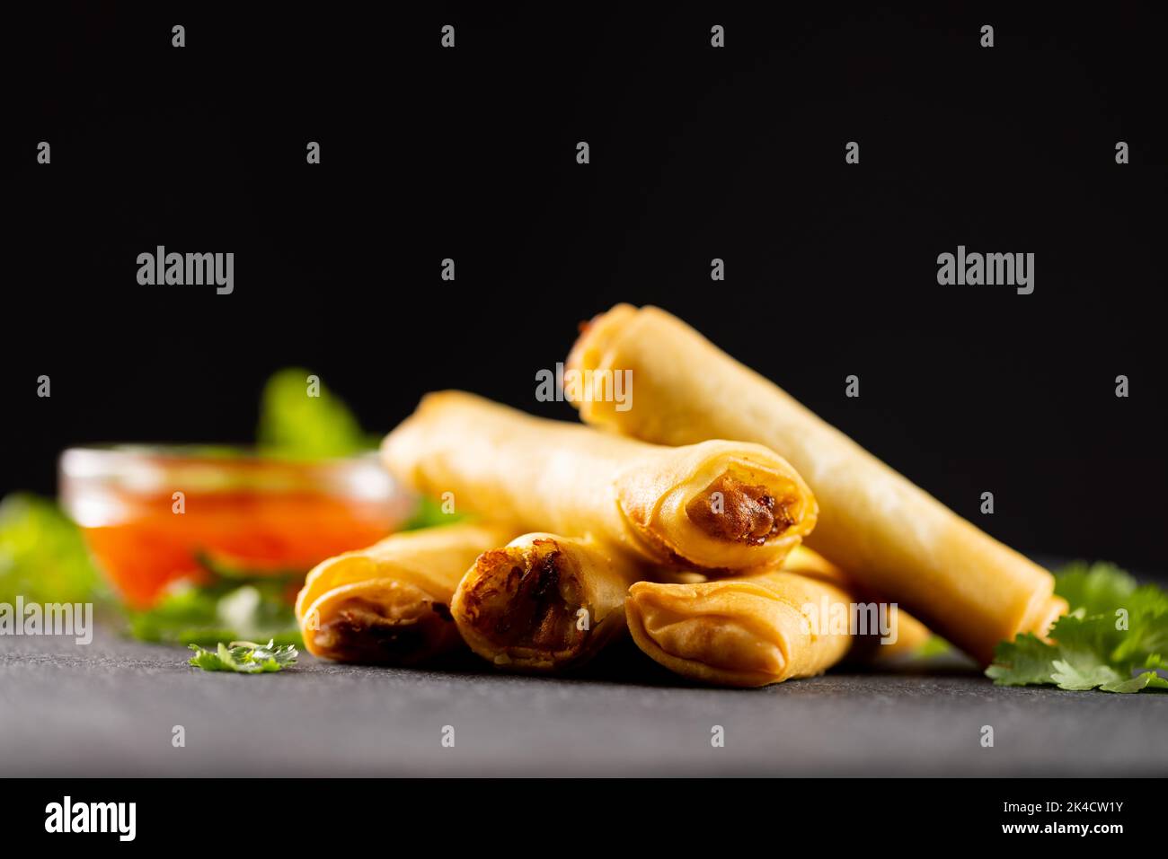 Close up of asian spring rolls, sliced lime and chilli sauce on grey ...