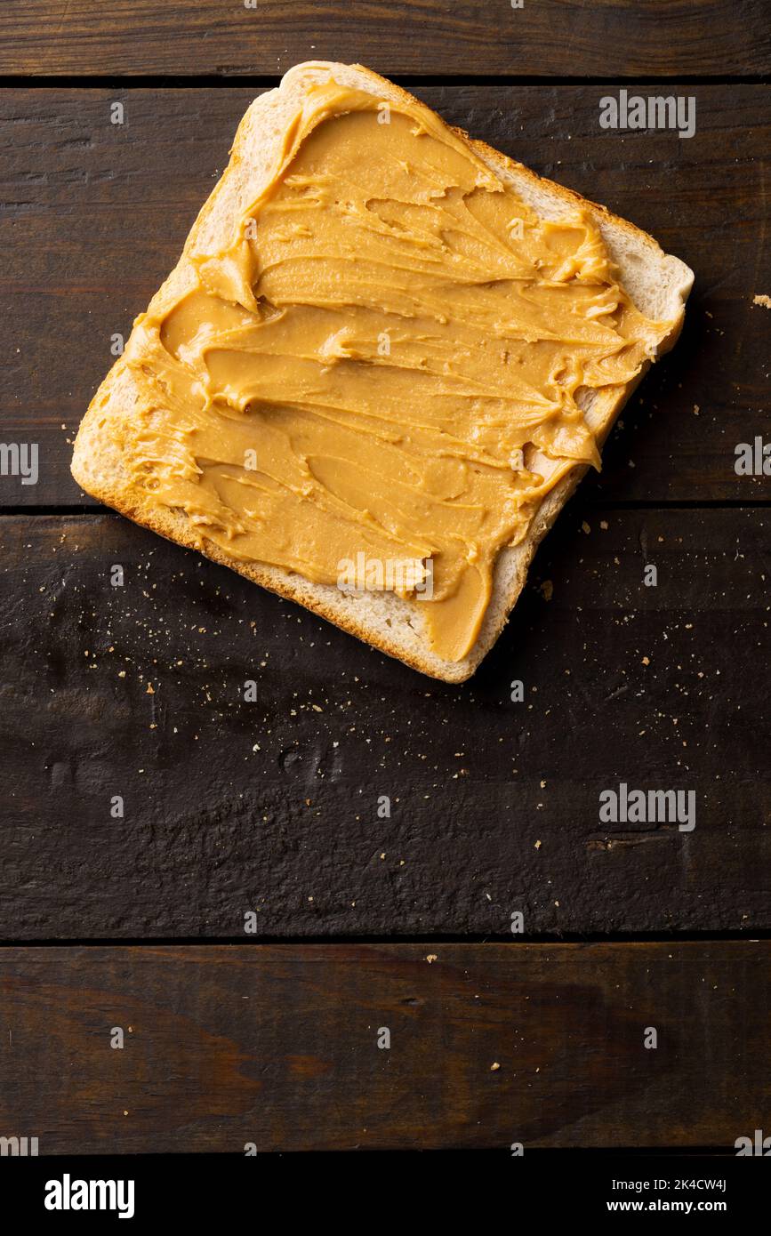 Vertical image of bread slice with peanut butter on wooden surface ...