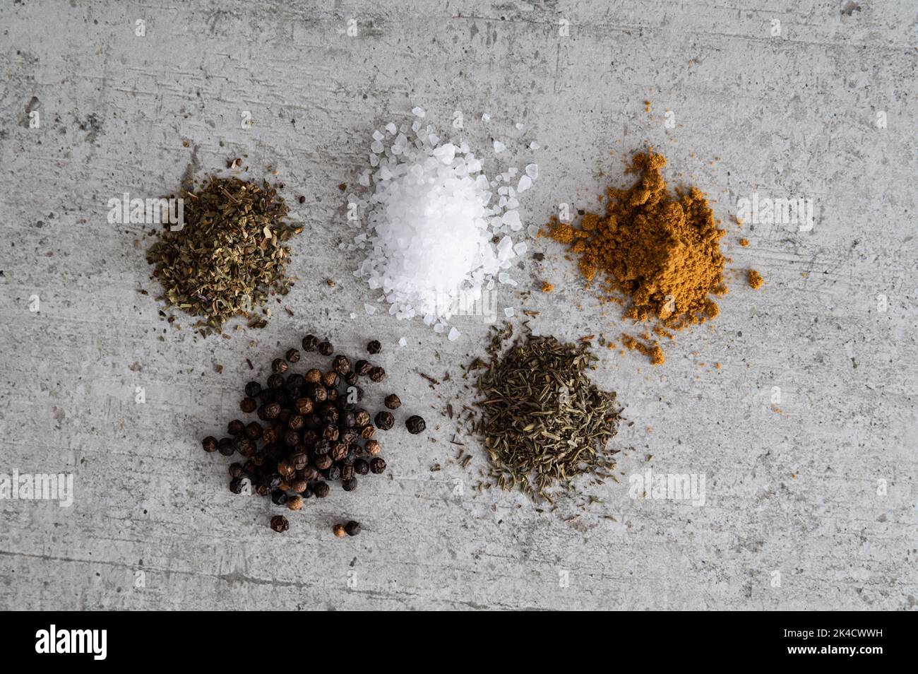 A top view of a gray surface with small piles of spices and seasonings ...