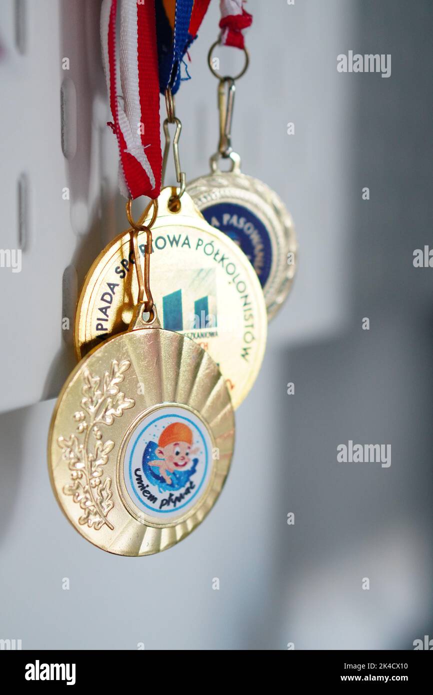 A vertical shot of three hanging gold-colored medals from school events ...