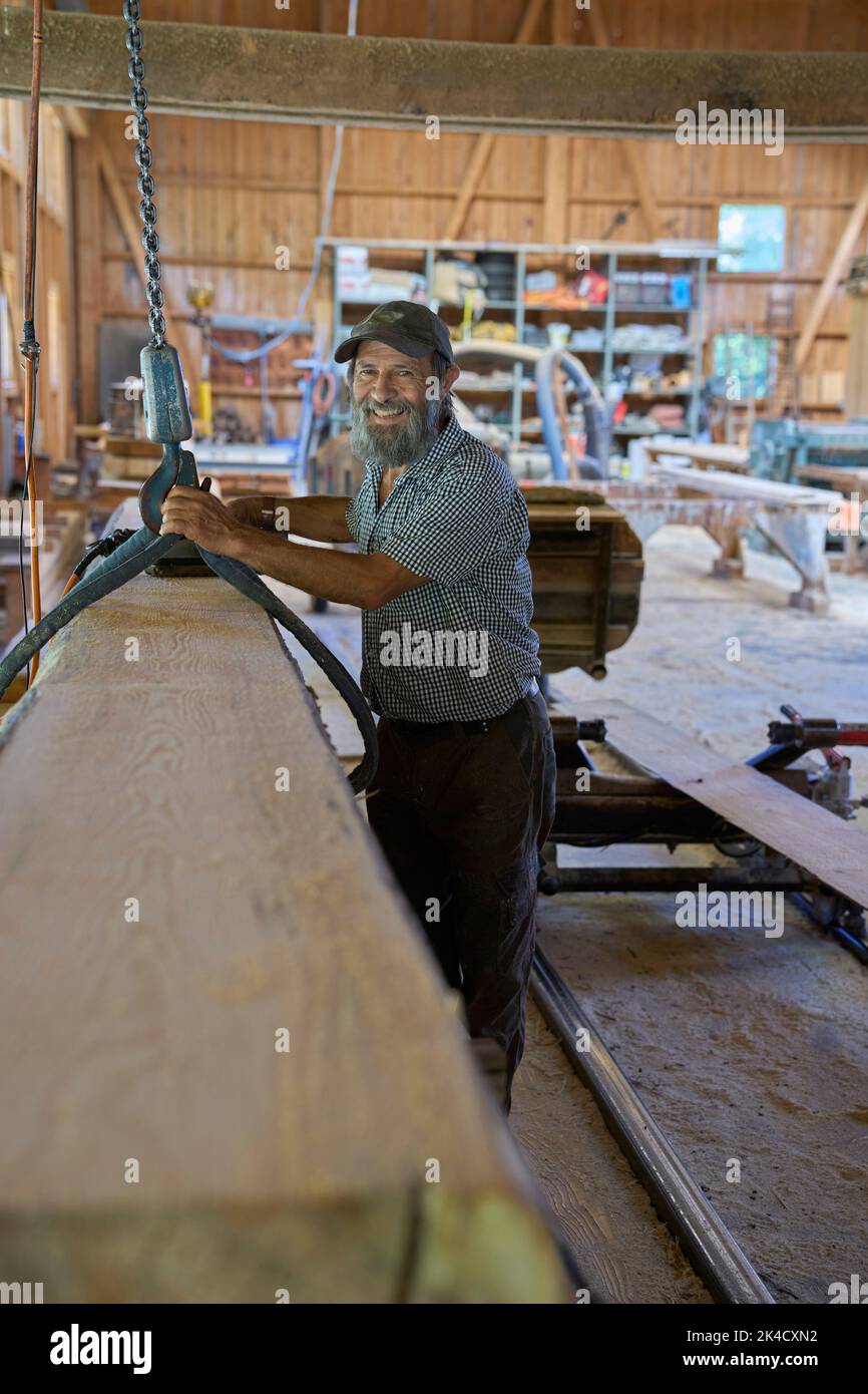 A vertical shot of a carpenter working in a sawmill on a wood ...