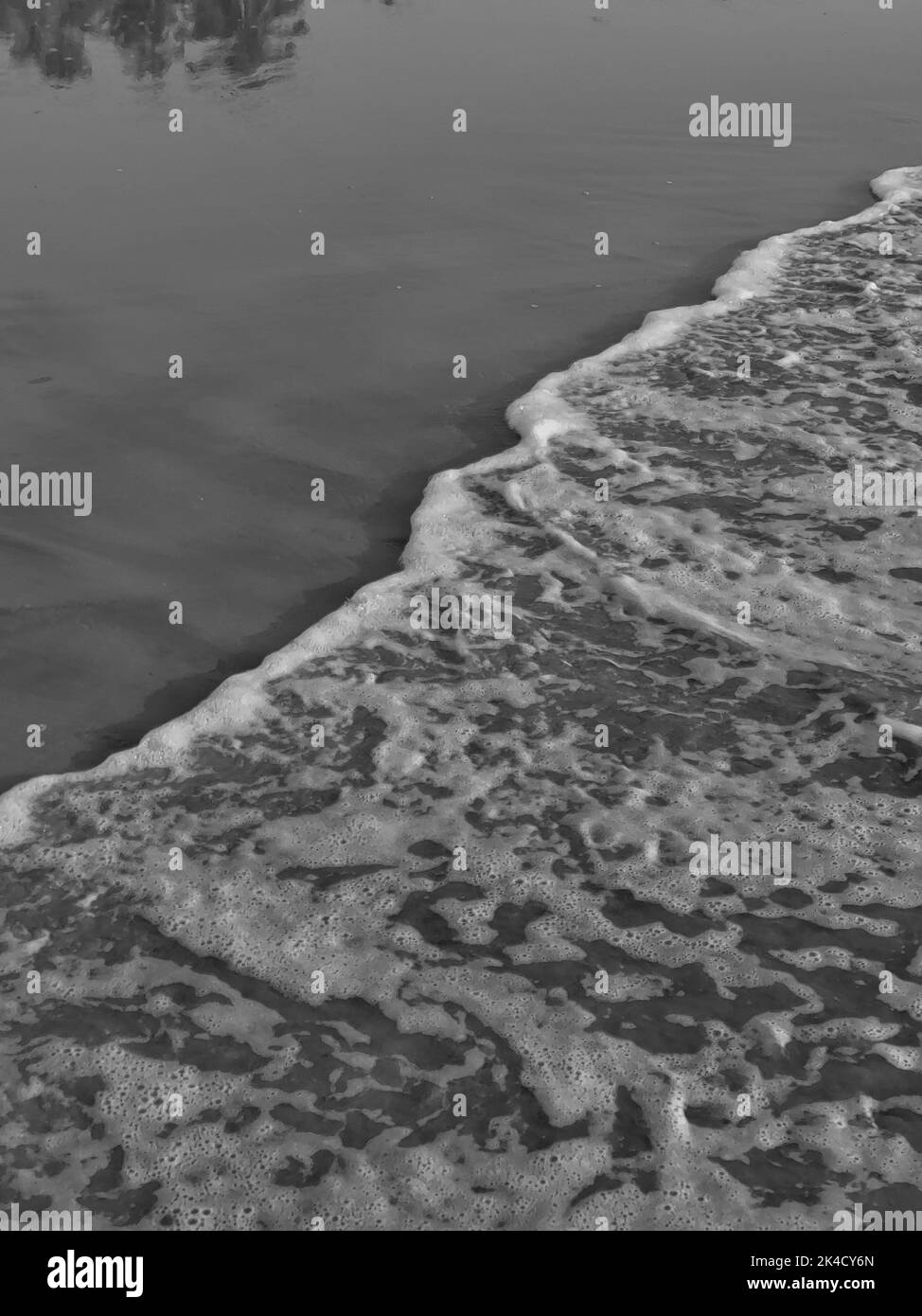 A vertical greyscale shot of the wet beach sand Stock Photo - Alamy