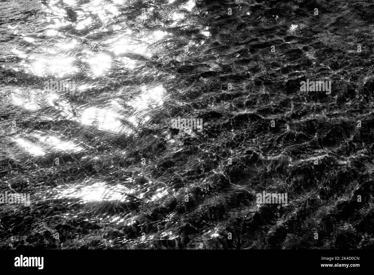 A top view grayscale of ocean water with the sunlight reflecting on it ...