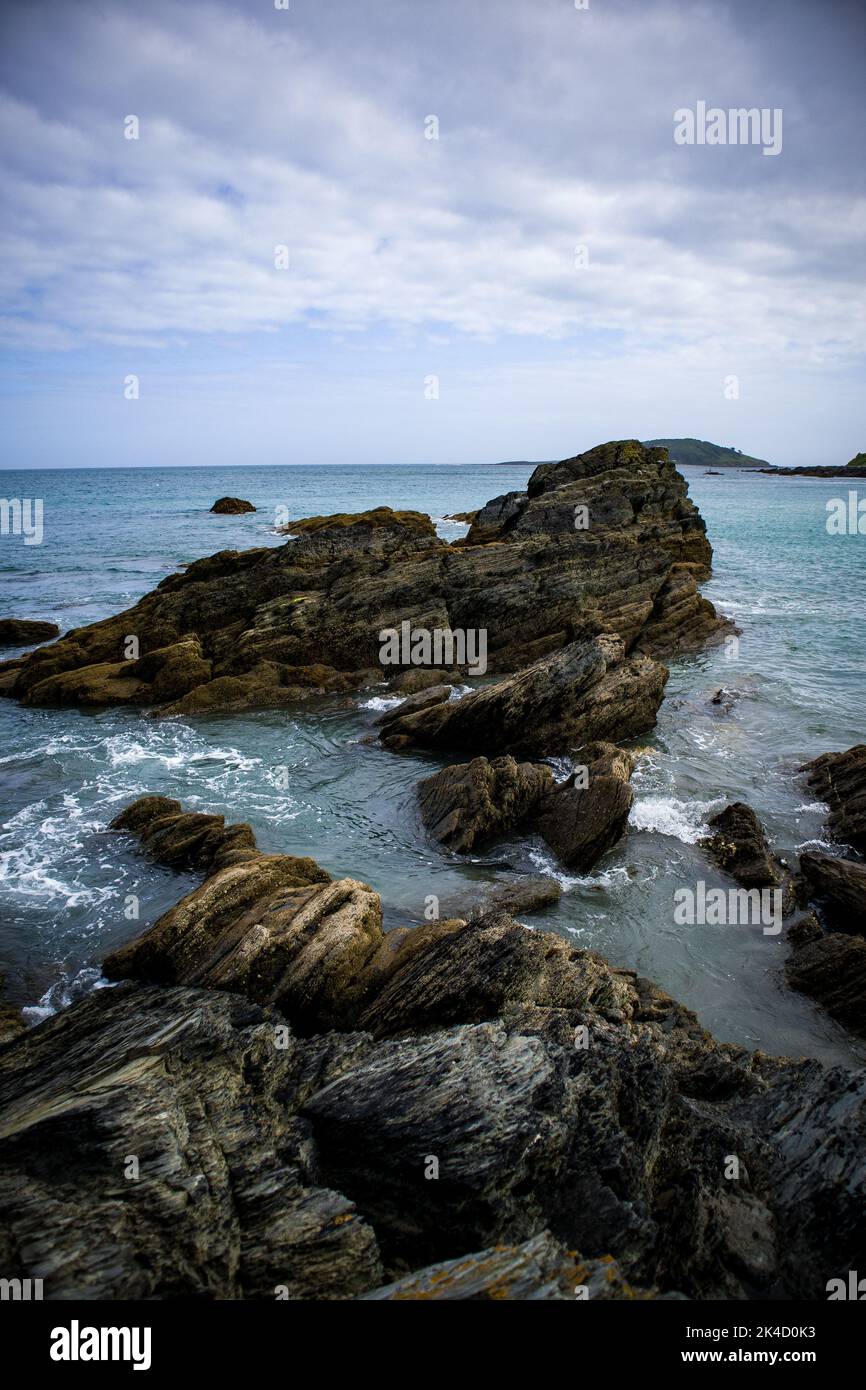 A vertical shot of foamy ocean waves crashing onto a rock Stock Photo ...