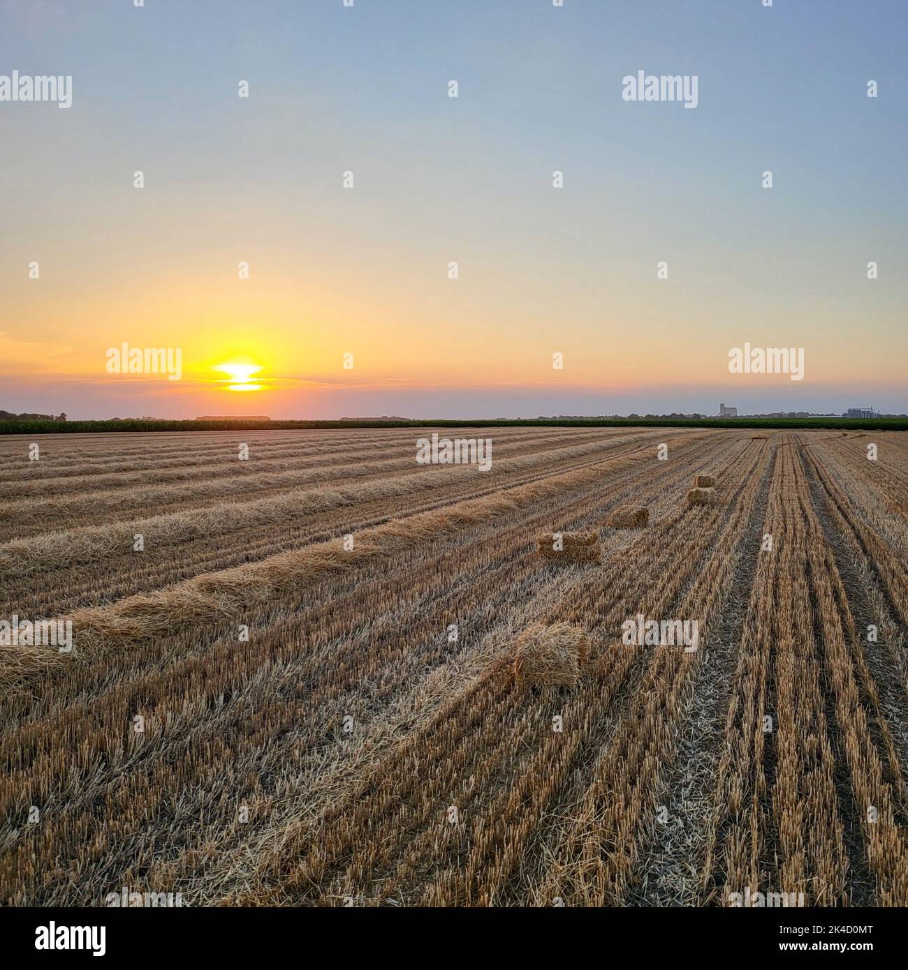 A beautiful shot of a sunset over a wheat field after harvest with hay ...