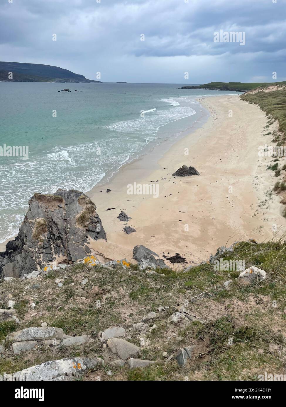 A vertical shot of a beach with low tides by the shore under a cloudy ...
