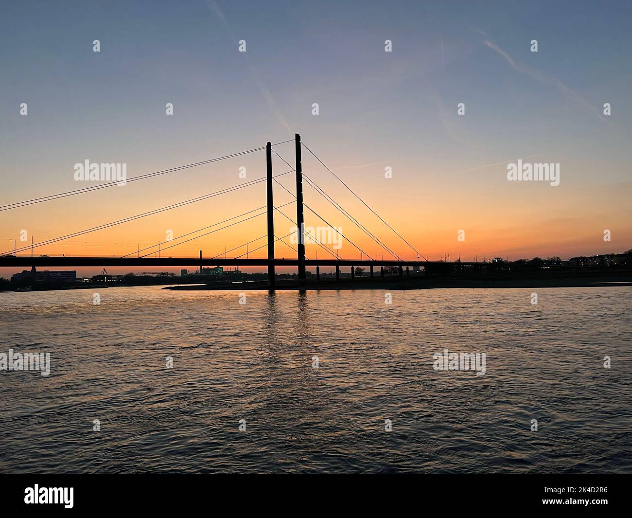 A beautiful sunset sky over a suspension bridge in Dusseldorf, Germany ...