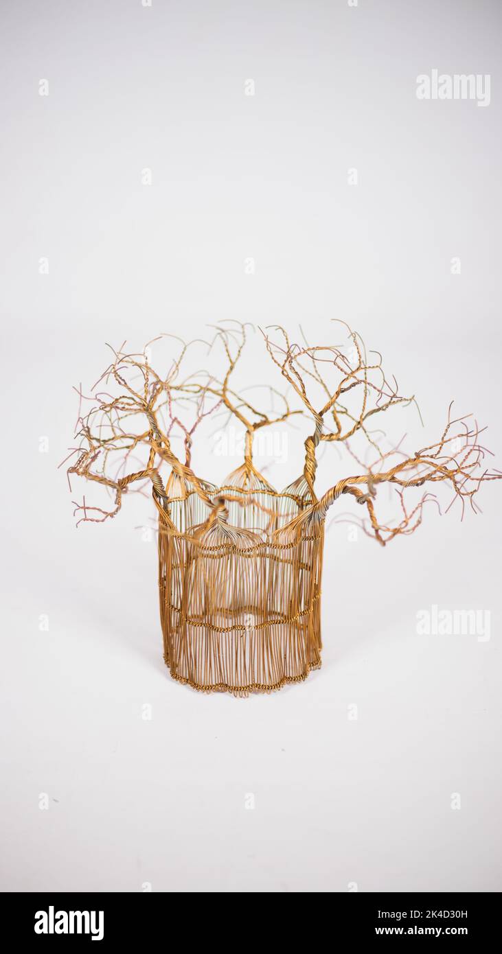 An abstract cage with sharp leafless trees on top of it woven from gold ...