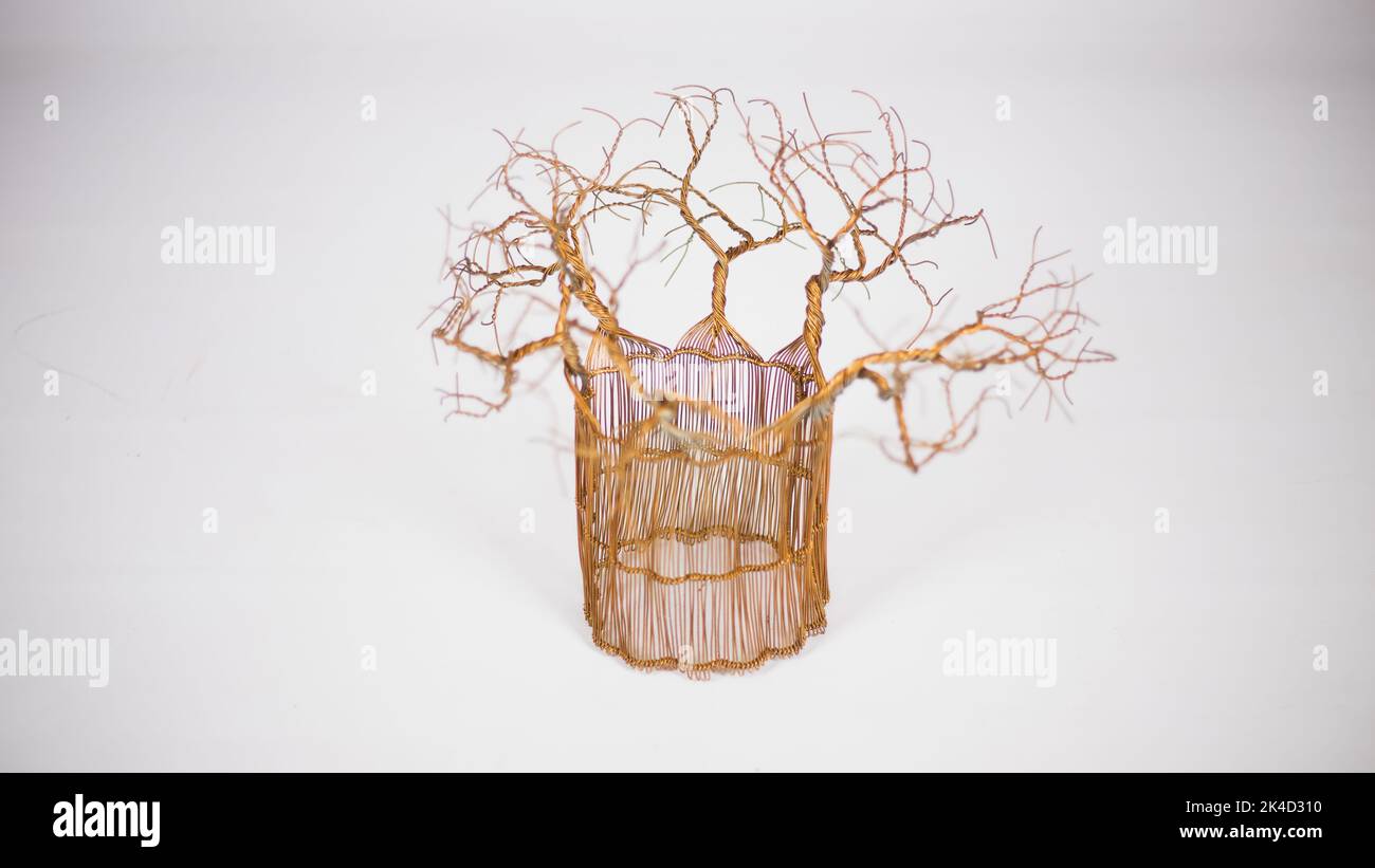 An abstract cage with sharp leafless trees on top of it woven from gold ...