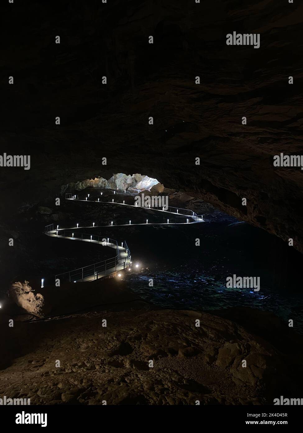A vertical shot of an illuminated walkway in a cave Stock Photo - Alamy