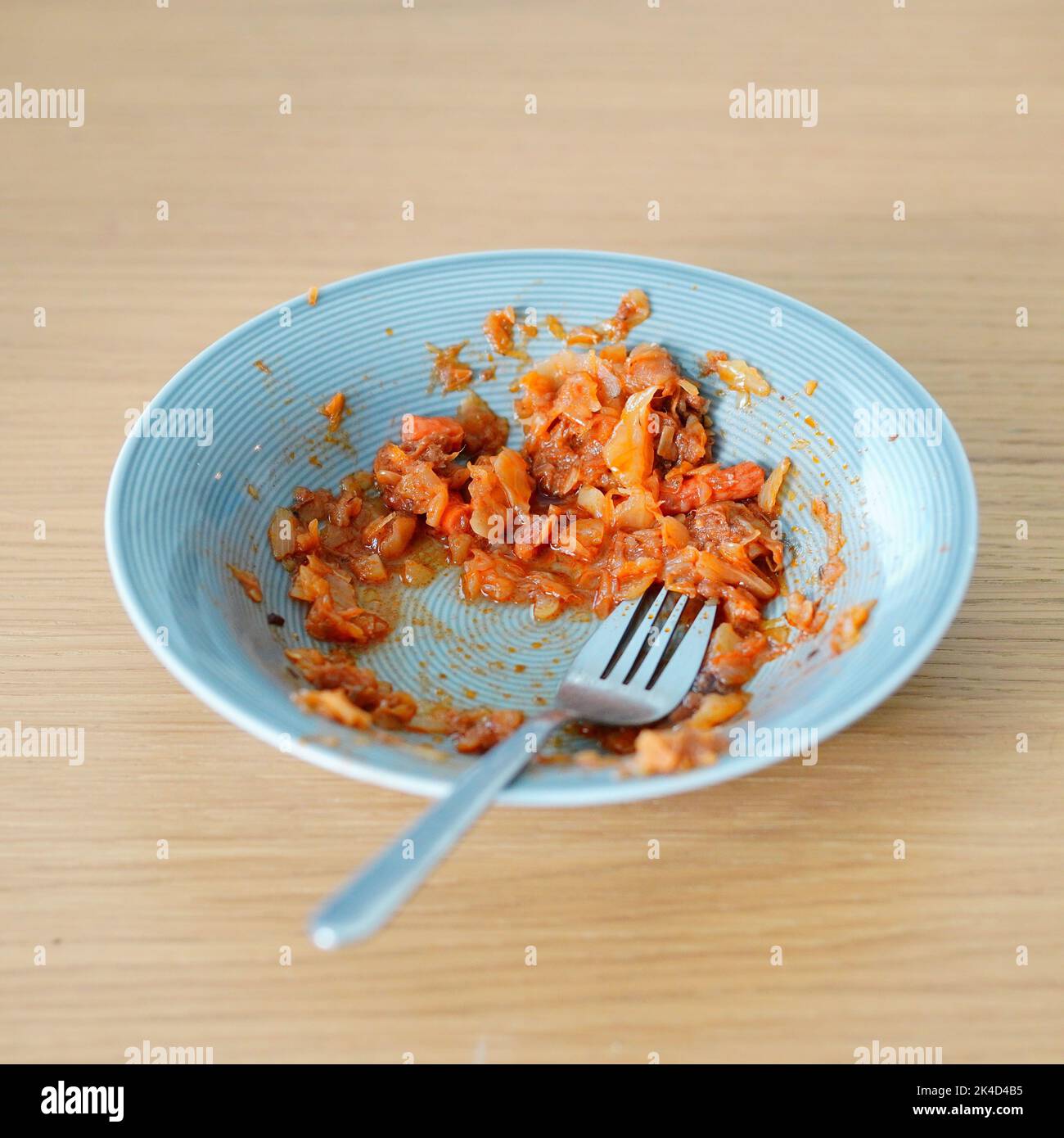 A close-up shot of a blue plate on wooden table with food remains Stock ...