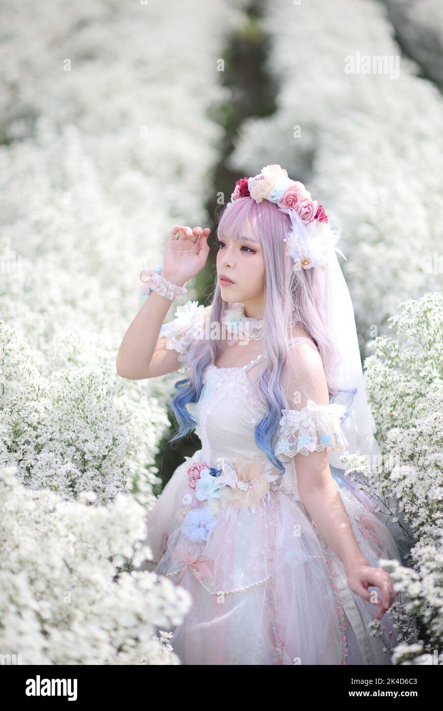 Beautiful young woman with white lolita dress with flowers garden ...