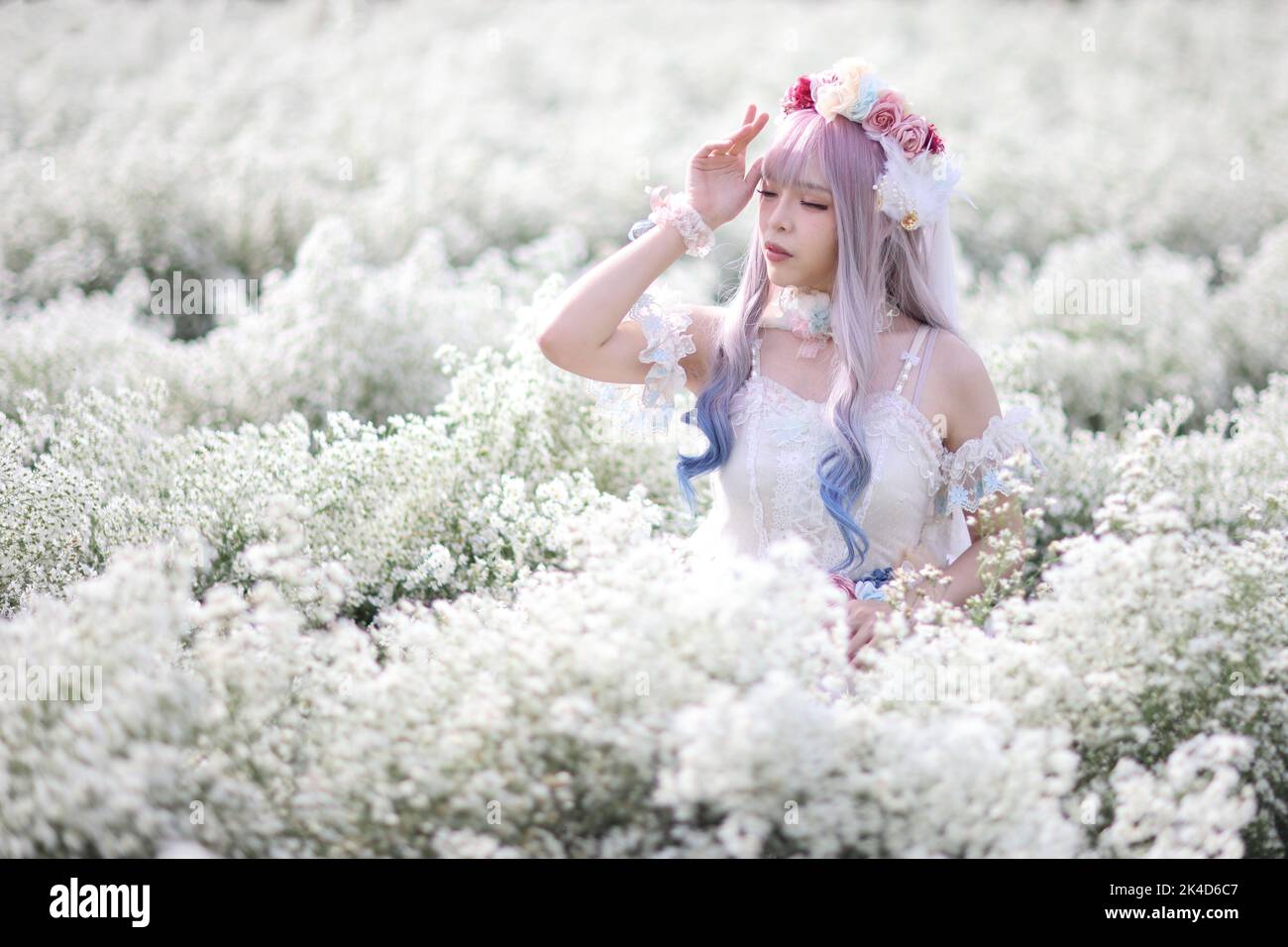 Beautiful young woman with white lolita dress with flowers garden ...