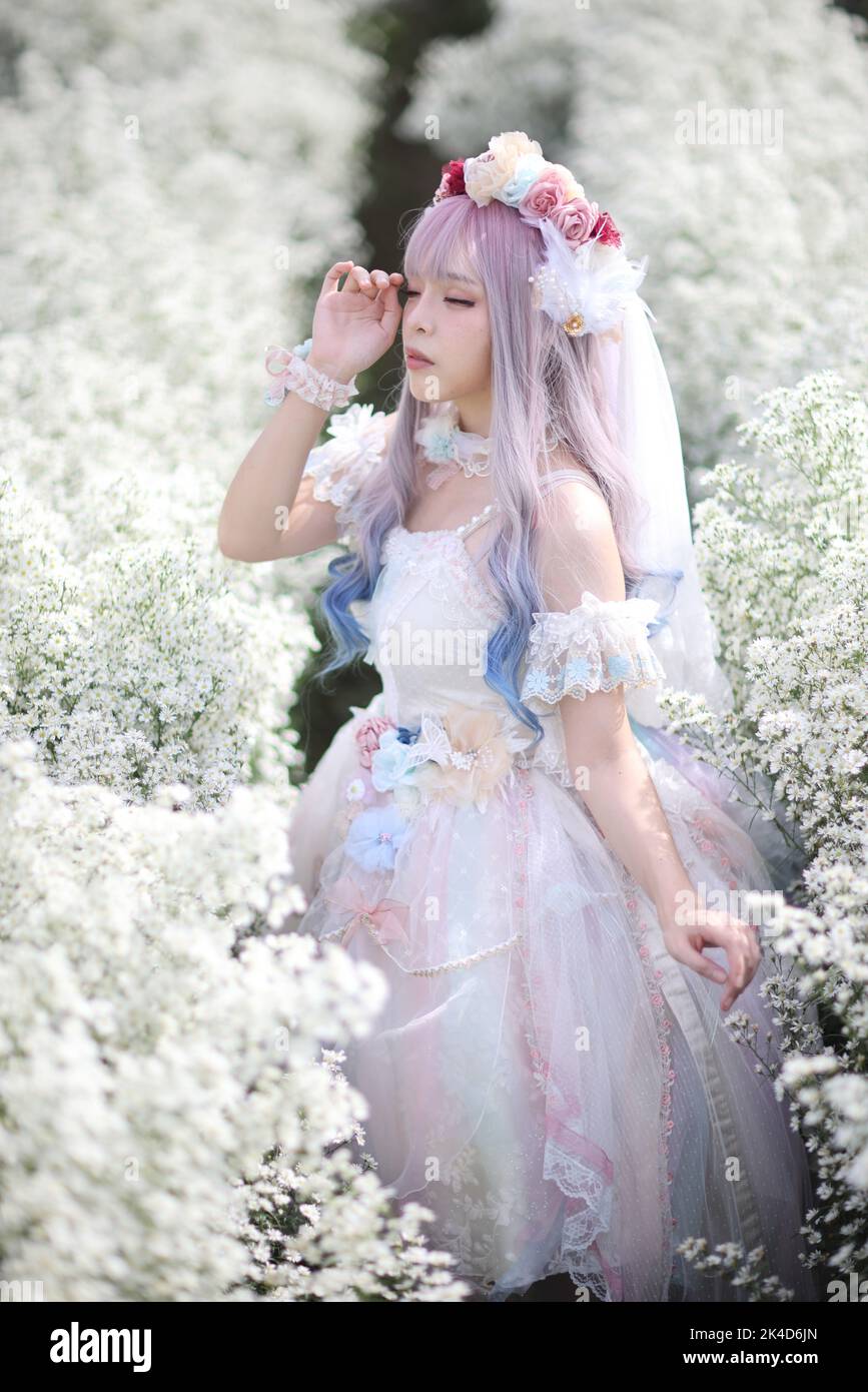 Beautiful young woman with white lolita dress with flowers garden ...