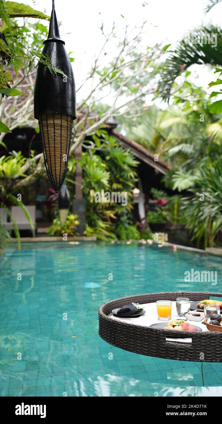 A vertical shot of a round tray with food and drinks in the pool ...