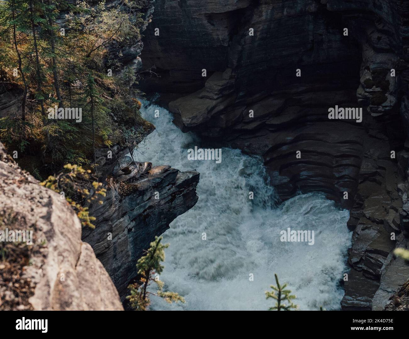 A high-angle shot of of the Athabasca Fall surrounded by rocks in ...