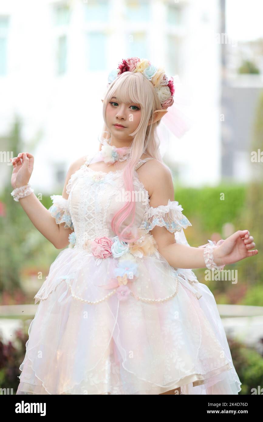 Beautiful young woman with white lolita dress with flowers garden ...