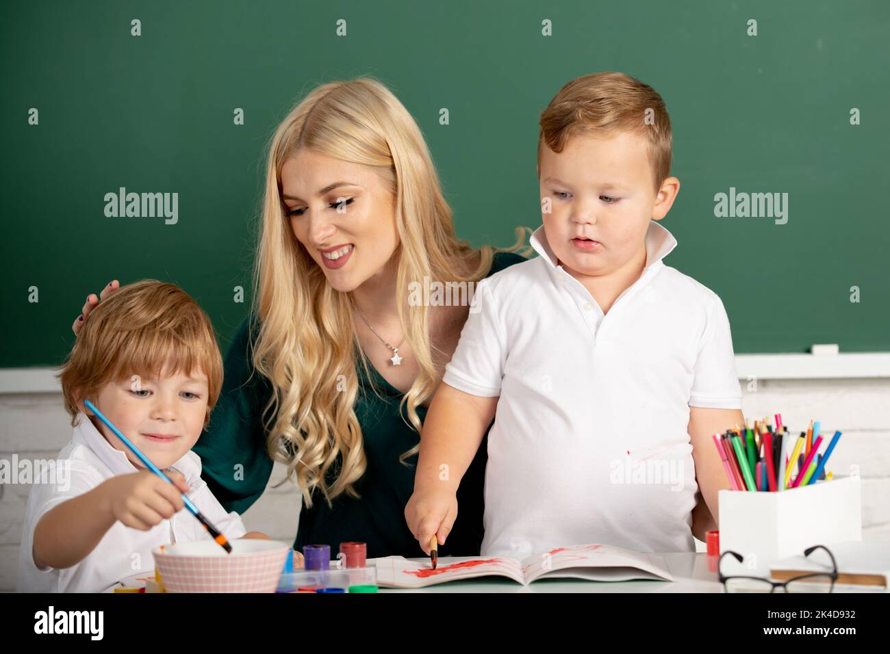 Little children with kindergarten teacher drawing at table indoors ...