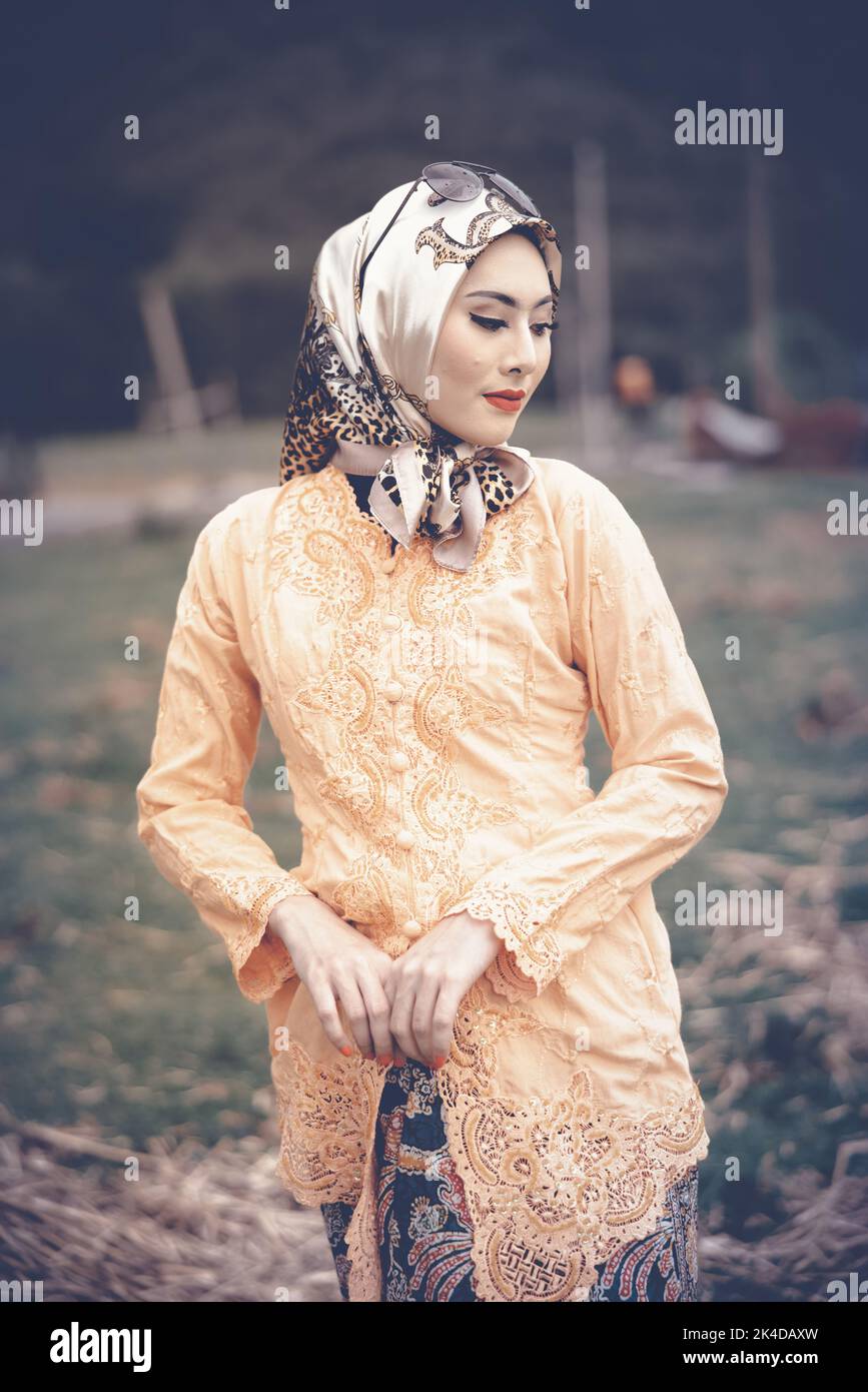 A vertical closeup of a beautiful female wearing yellow kebaya (Malay ...