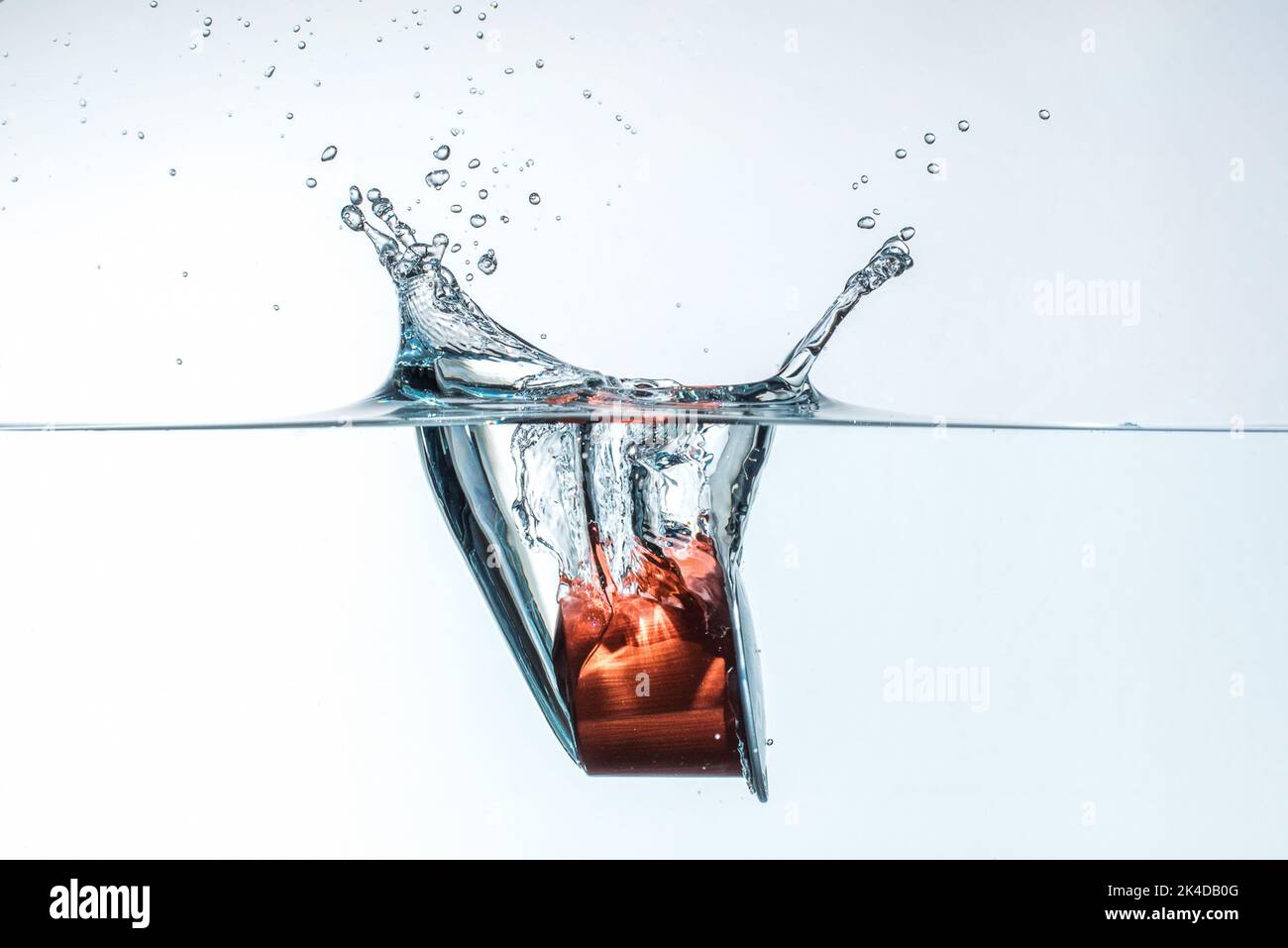 A closeup of an ice cube falling into the water with splash in the white background Stock Photo ...