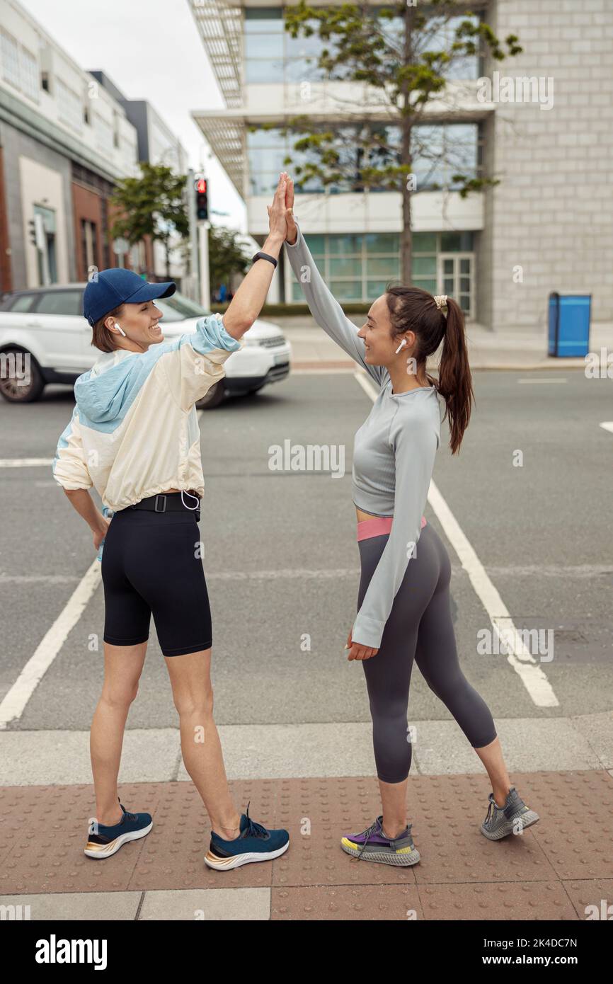 Two sportive young female friends walking city after morning running ...