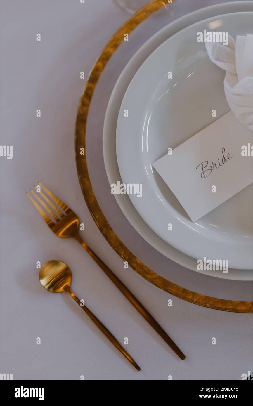 A golden spoon and fork next to a card for the bride lying on a plate ...