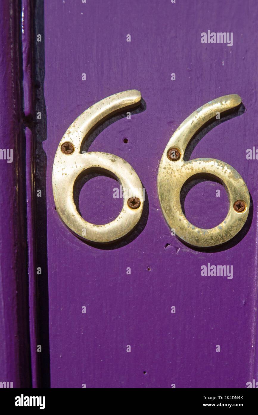 Purple painted panel with brass numbers 66 screwed to it. Photographed ...