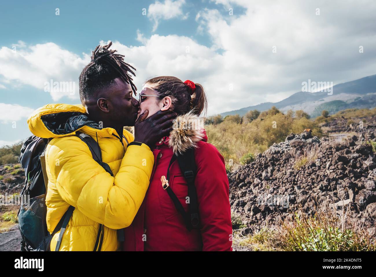 Multiethnic couple of young hikers on vacation kissing against the ...