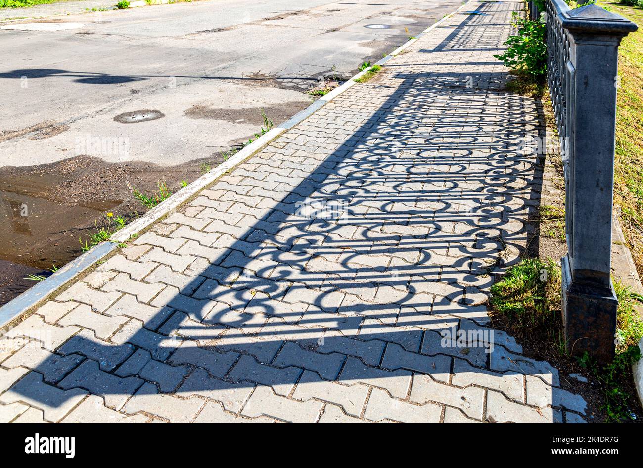 Shadow from the city decorative grating on the pavement. Rhythm and ...