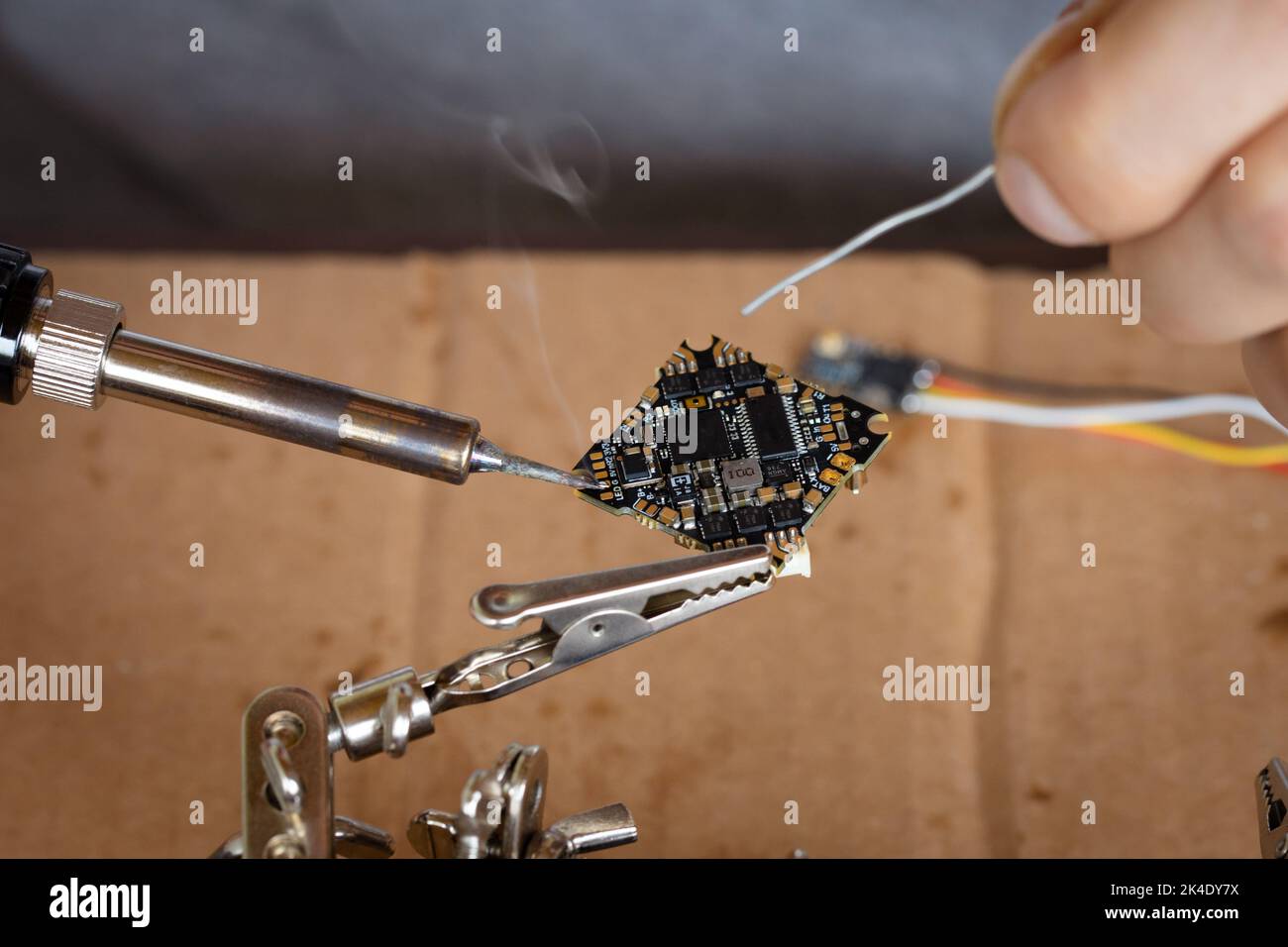 The hand holding the tin, a soldering iron solder the chip in place. a ...